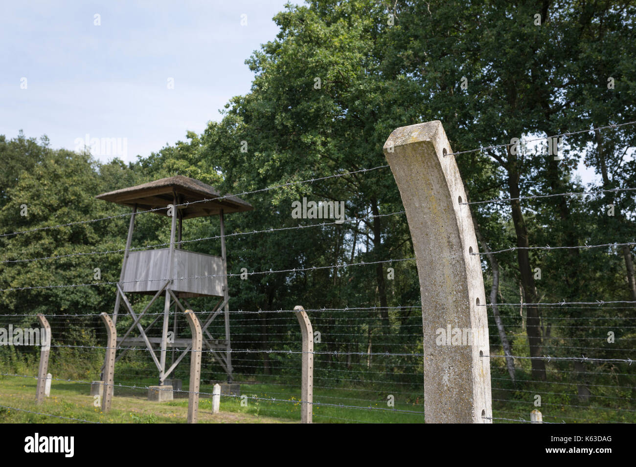 Fence with barbed wire and a watchtower at former concentration camp ...