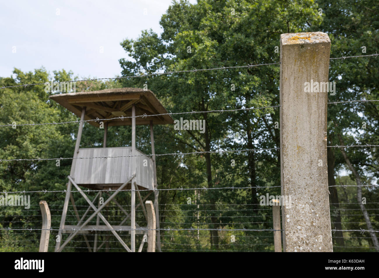 Fence with barbed wire and a watchtower at former concentration camp ...