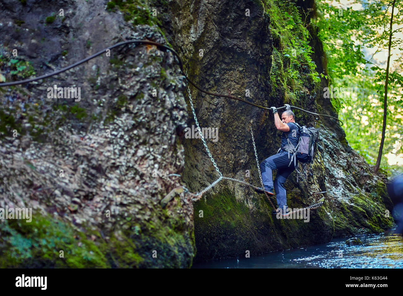 Man climbing on safety cable and chains on the mountain wall Stock ...