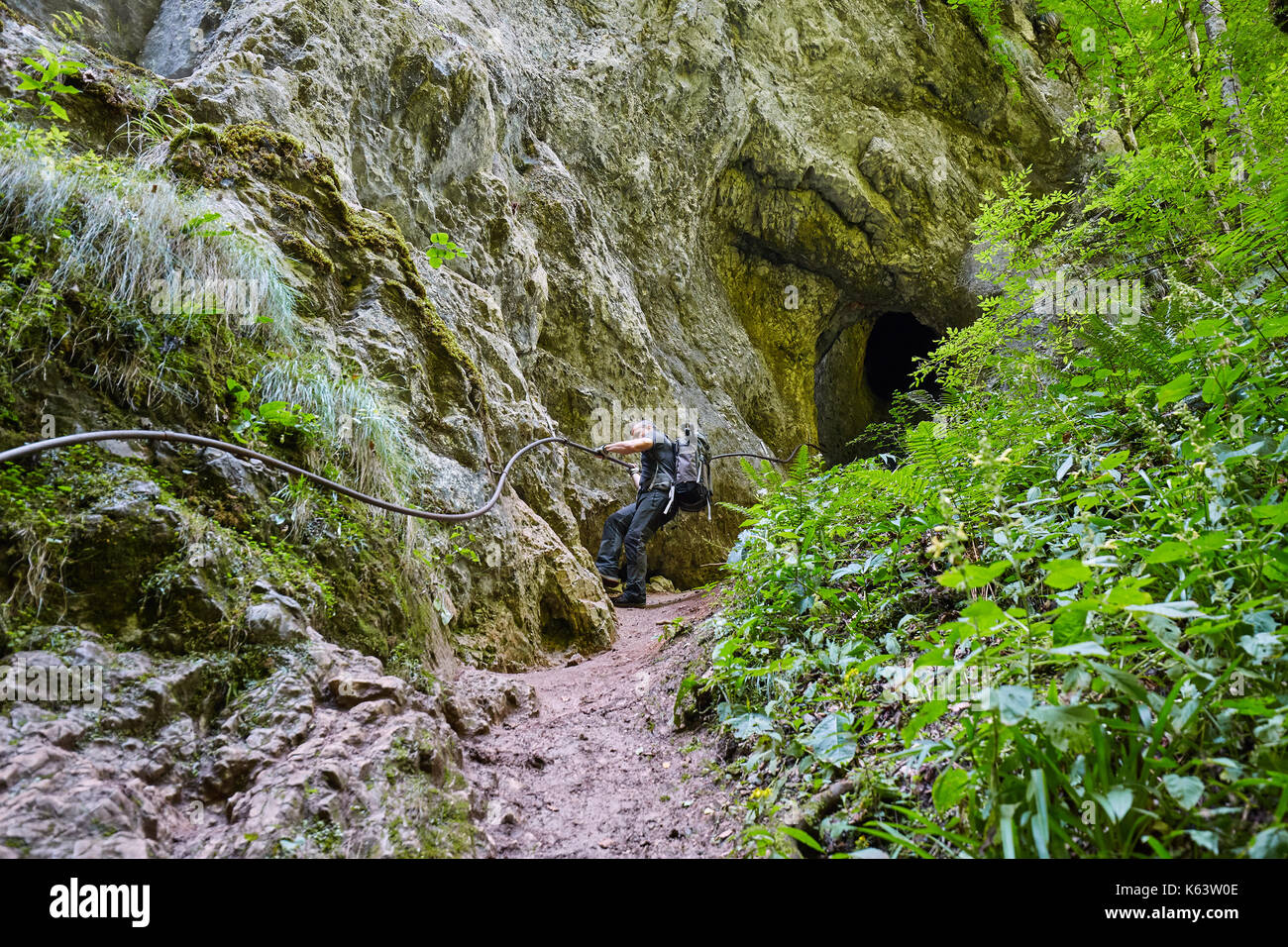 Man climbing down on safety chain from a cave Stock Photo - Alamy