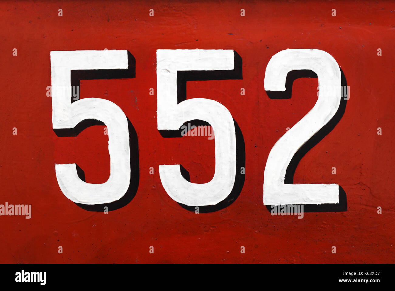 White dimensional number 552 on a dark red background in a close up ...