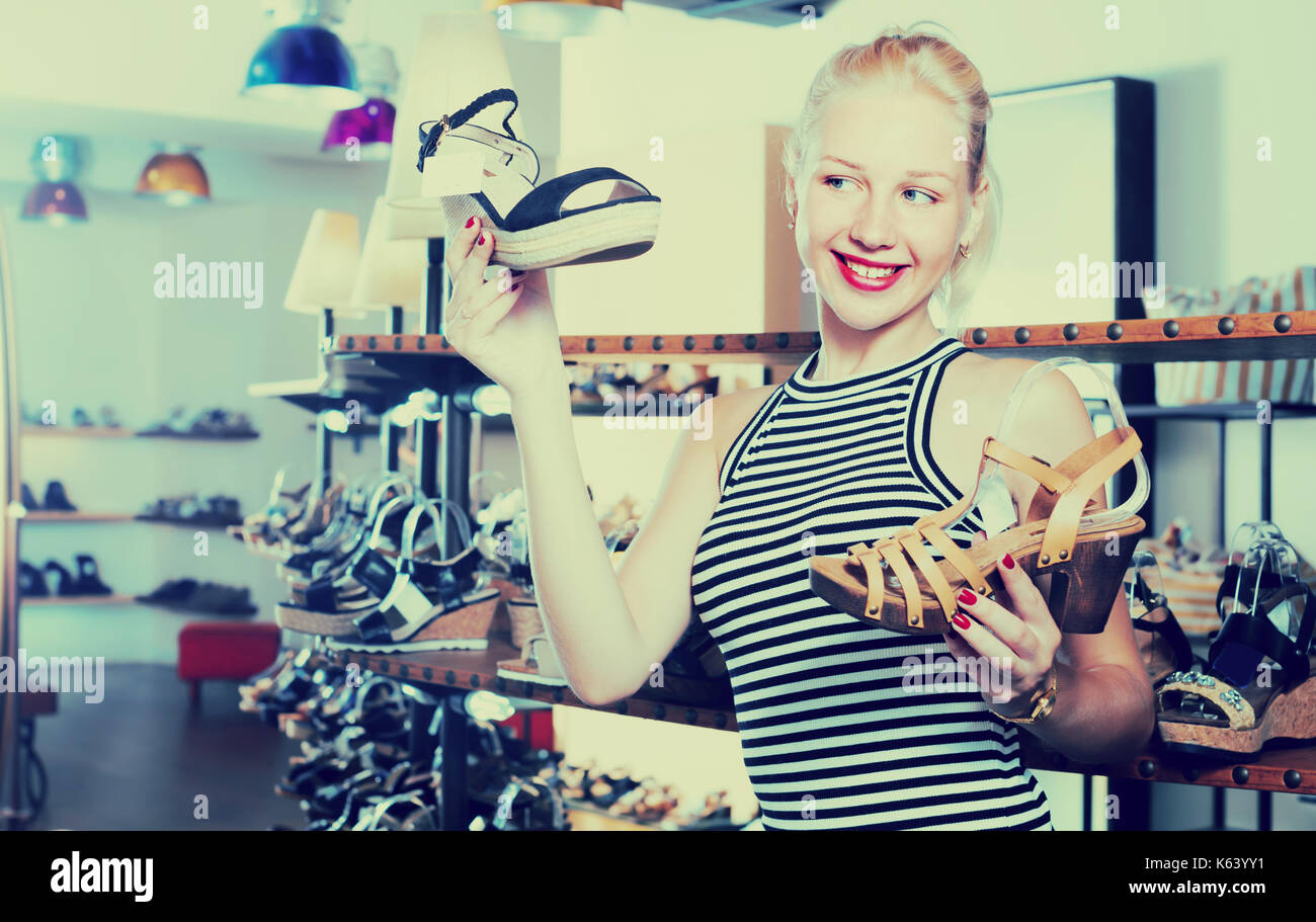 Adult woman choosing and comparing two pairs of new shoes in shop Stock ...