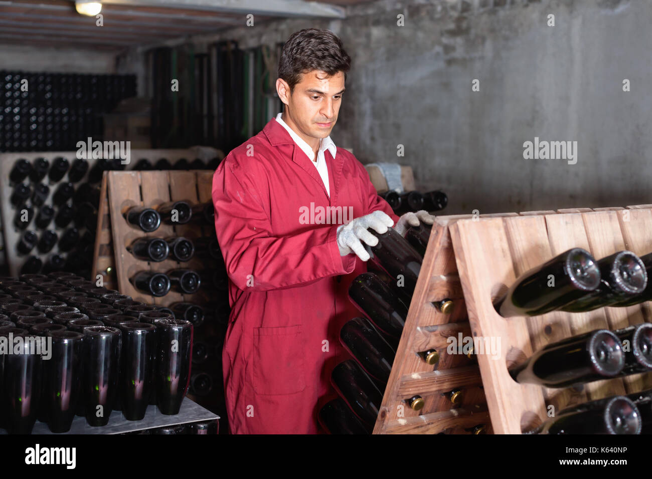 Attentive man winery employee wearing coat working in aging section ...