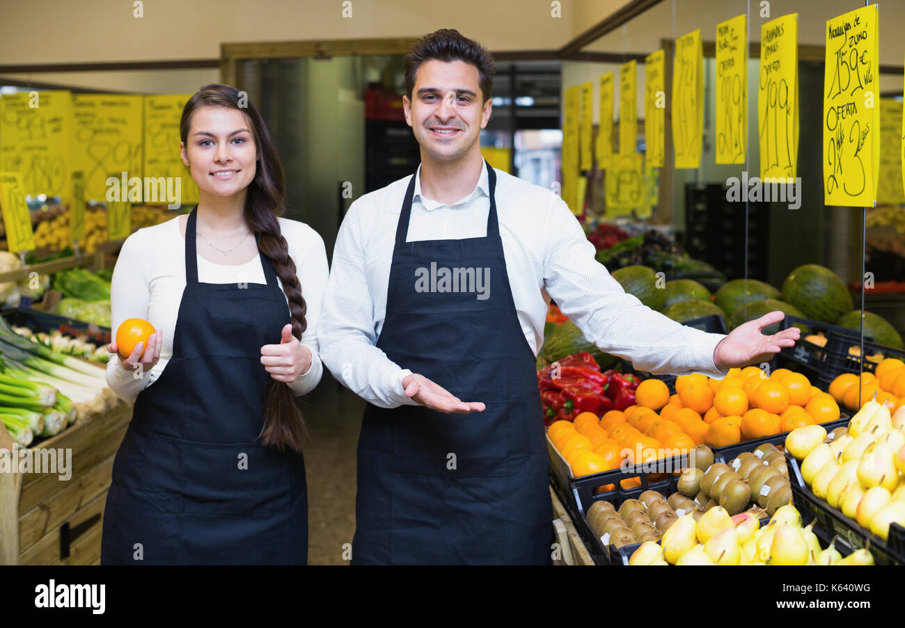 Positive smiling sellers offering good price for fruits in grocery ...