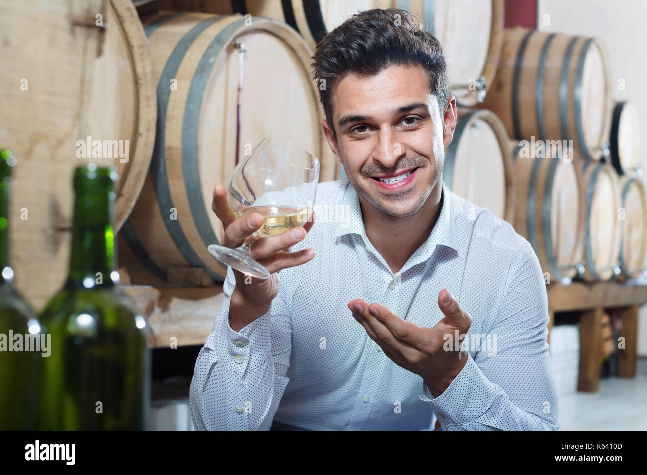 Portrait of positive man enjoying liquor sample in glass in section ...