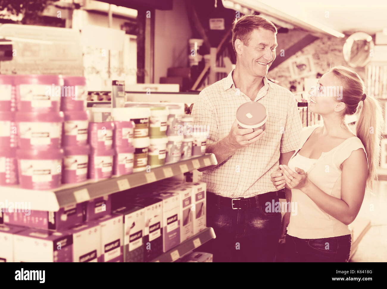 smiling man and woman customer buying paint tin in household store ...