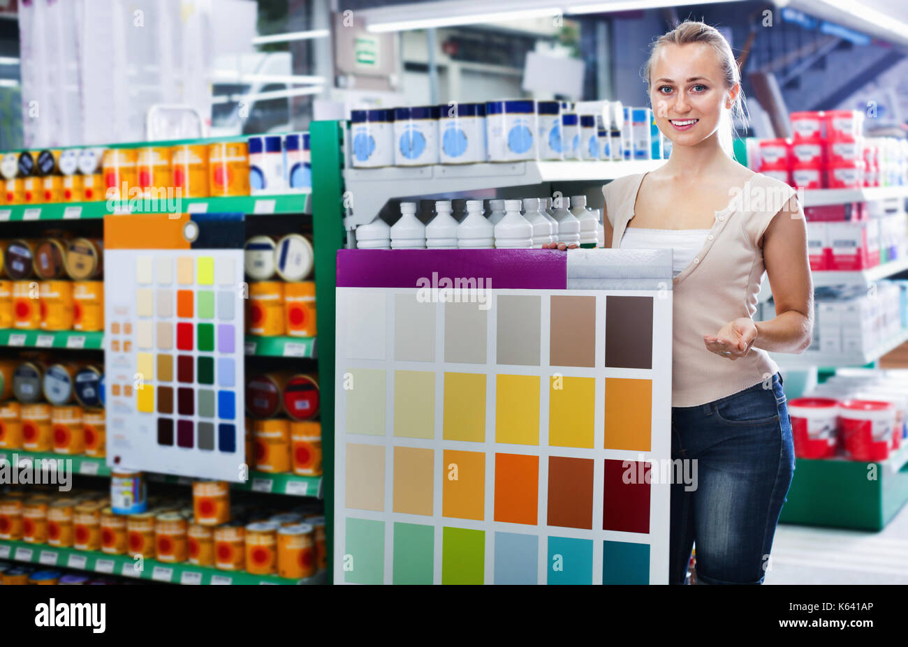 Smiling pleasant young woman choosing color for painting using palette ...