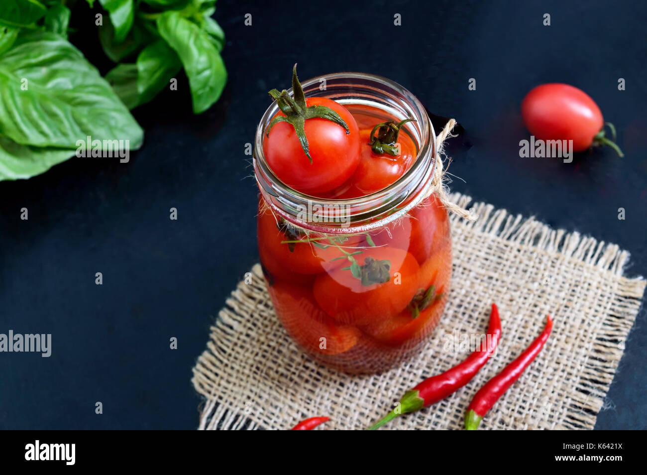 Sour tomatoes in a glass jar on a black background. Pickles Stock Photo ...