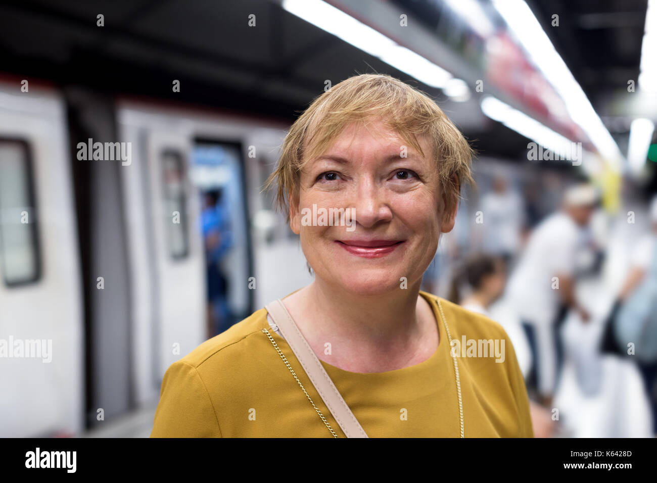 Positive mature woman commuter waiting train on public transport ...