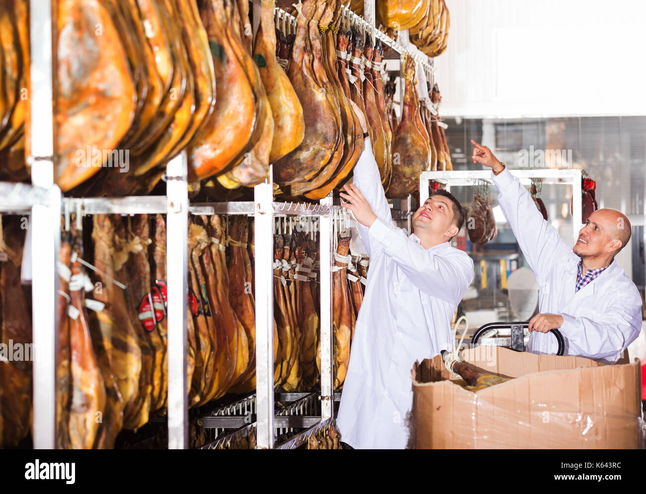 Mature butcher and assistant with the jamon joints at a meat factory ...