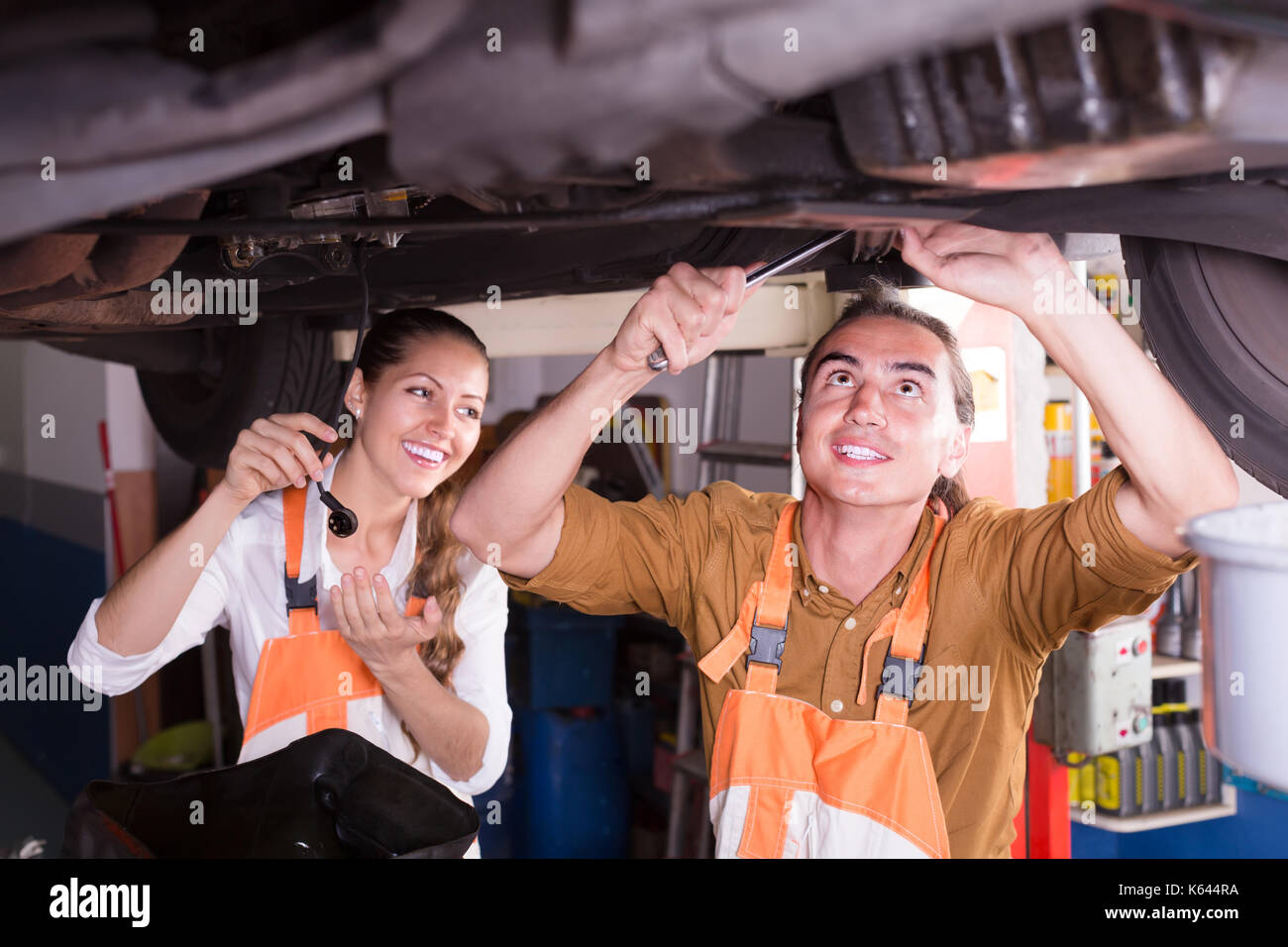Portrait of two cheerful auto mechanics repairing broken car at garage ...