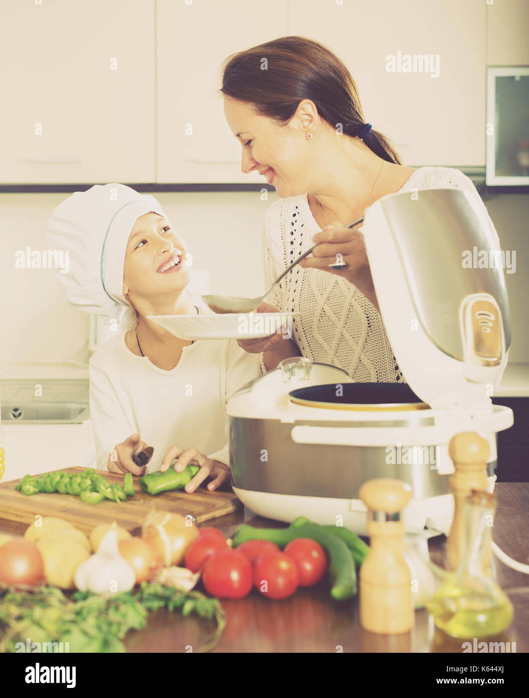 Happy 25-30 years old mother and little daughter using multicooker at ...