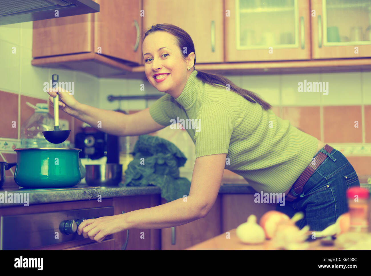 Portrait of happy smiling housewife cooking dinner in domestic kitchen ...