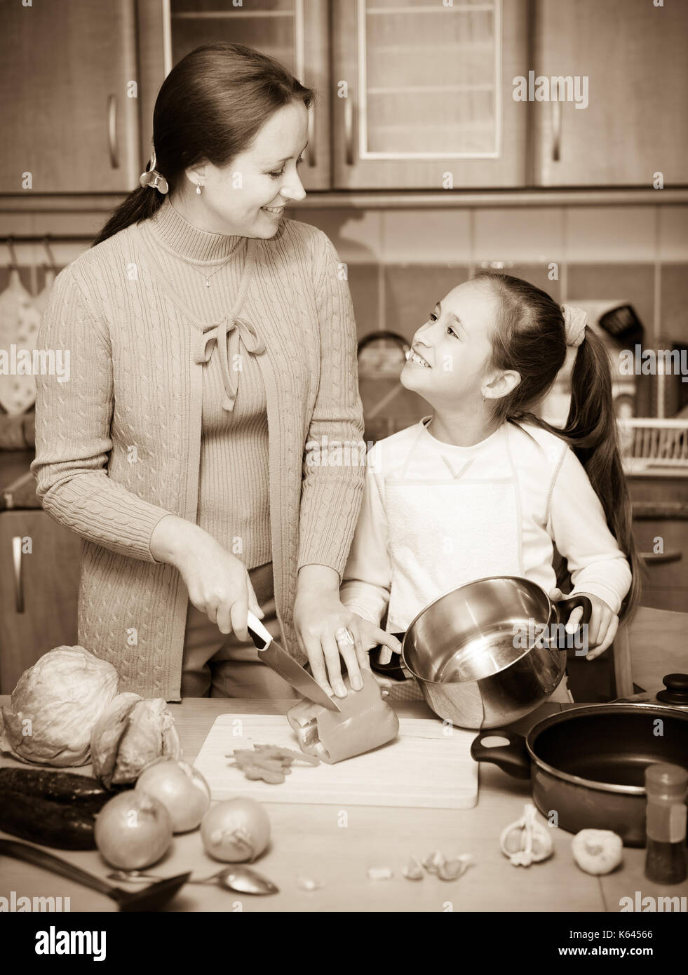 smiling little girl helping mother to make soup at kitchen Stock Photo ...