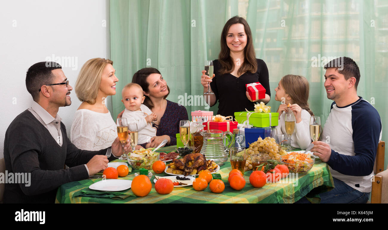 Cheerful smiling relatives congratulating family member with gifts and ...