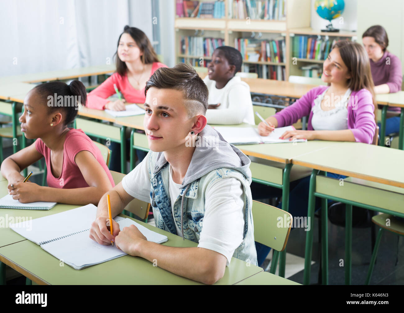Group of attentive pupils making the notes at the lesson in classroom ...