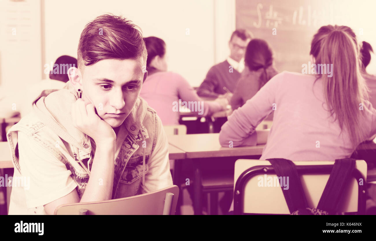 school pupil sitting away from classmates and feeling depressed Stock ...