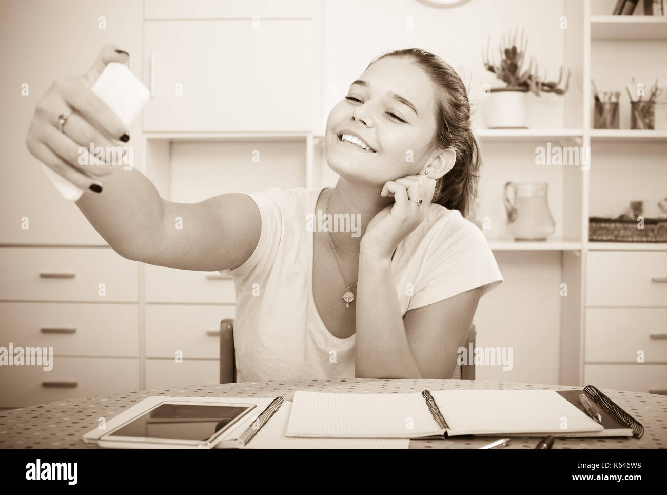 cheerful smiling female teenager doing selfie during homework at the ...