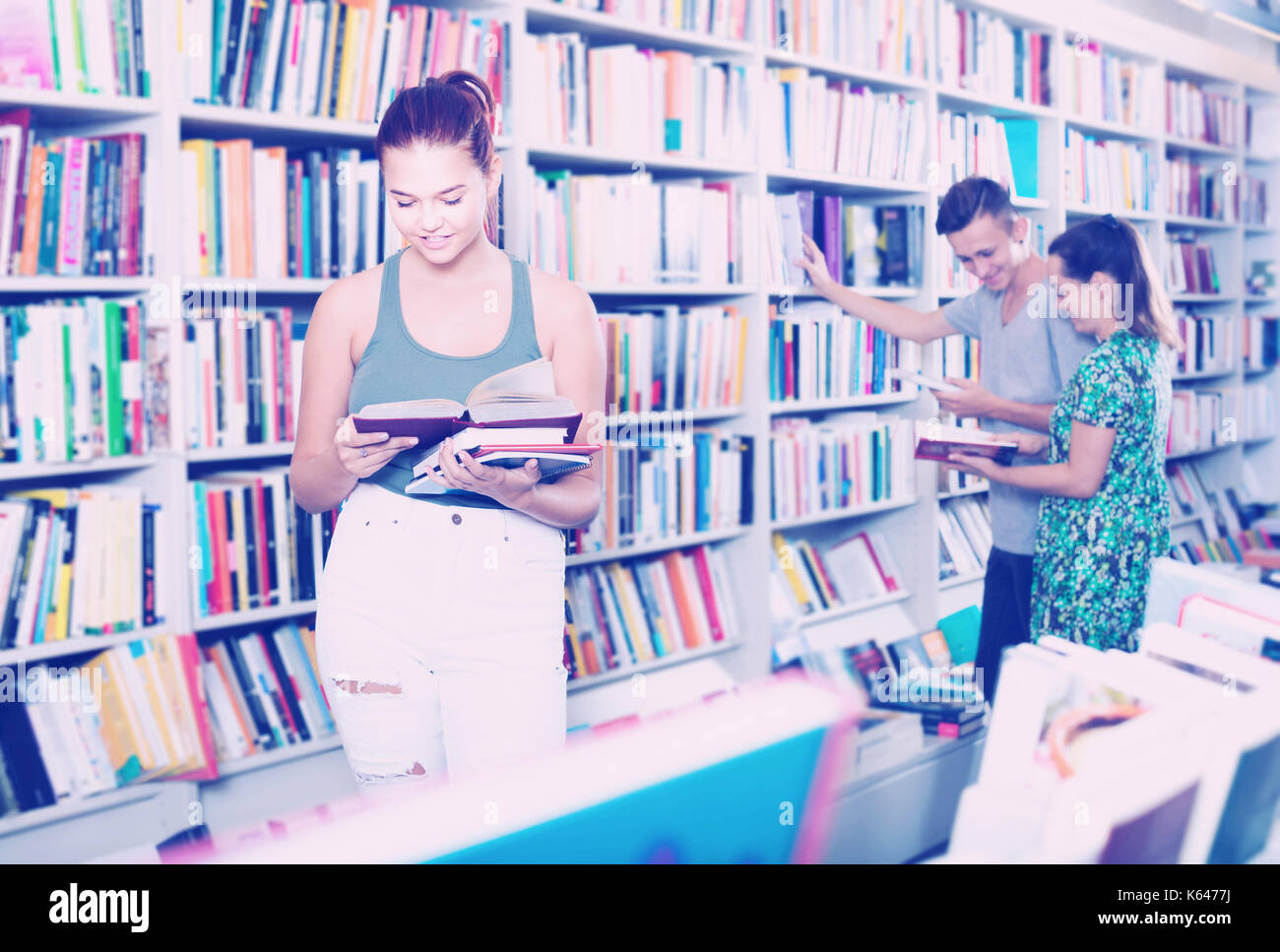 Interested teenager girl reading book while holding new literature in ...