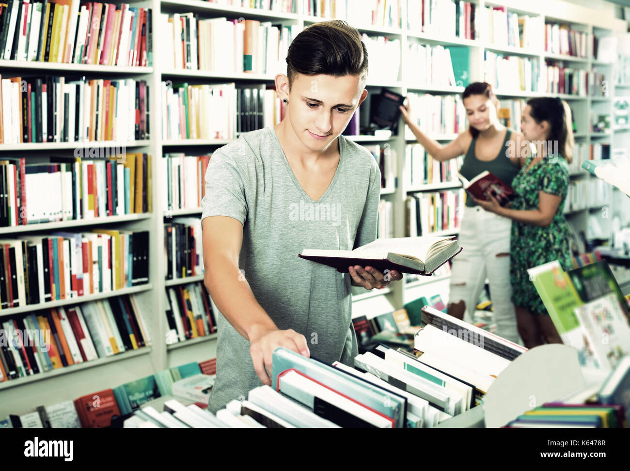 Cheerful young boy holding open book in hands and looking at it in ...