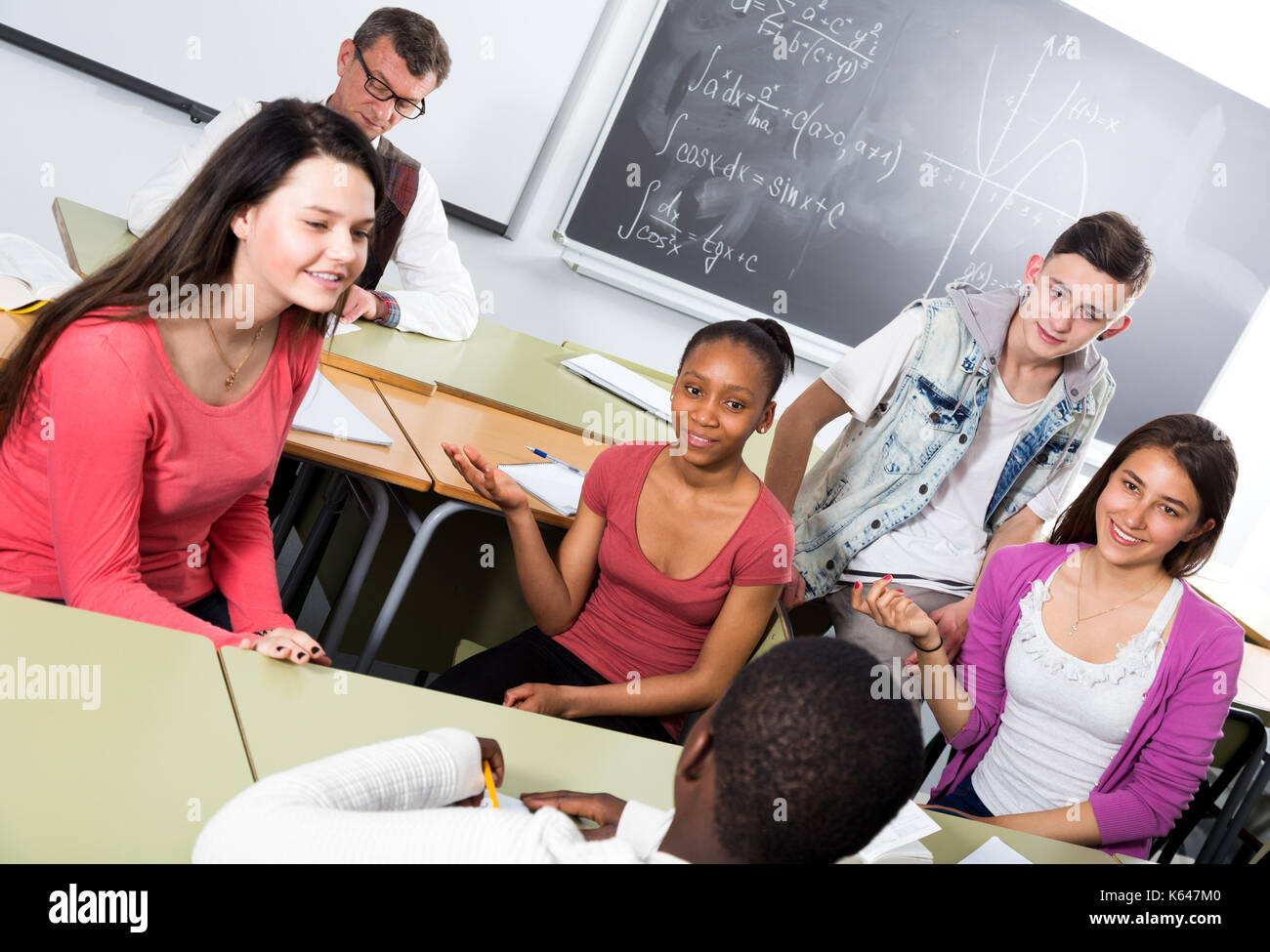 Cheerful students of different nationalities sitting and talking in the ...