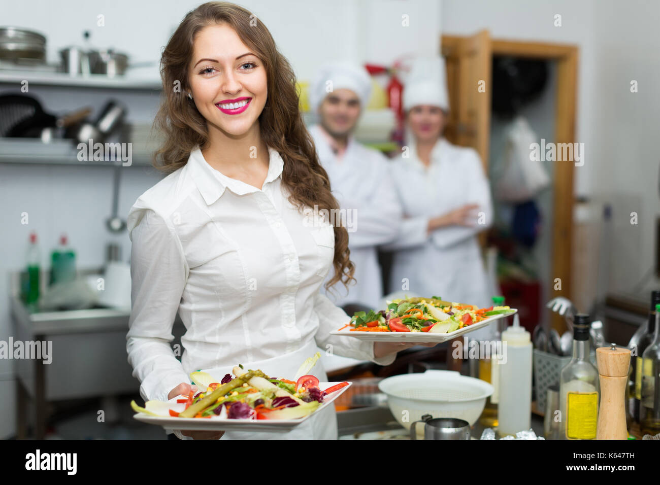 Beautiful smiling female waiter taking dish from kitchen Stock Photo ...