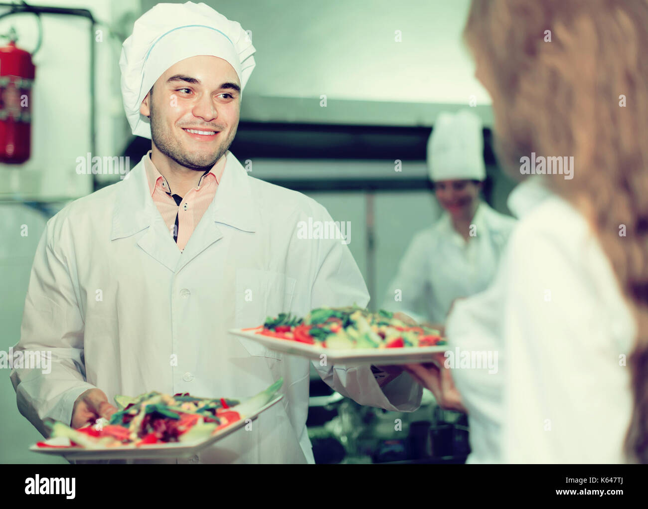 Female waiter taking dish from kitchen in cafe. Focus on man Stock ...