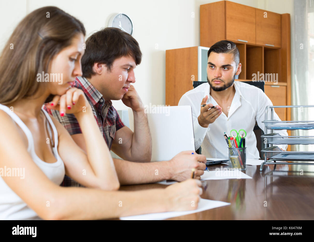 Agent clamouring credit repayment from couple at office Stock Photo - Alamy