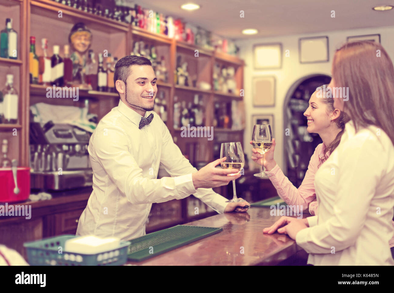 Smiling young bartender and cheerful women at bar Stock Photo - Alamy