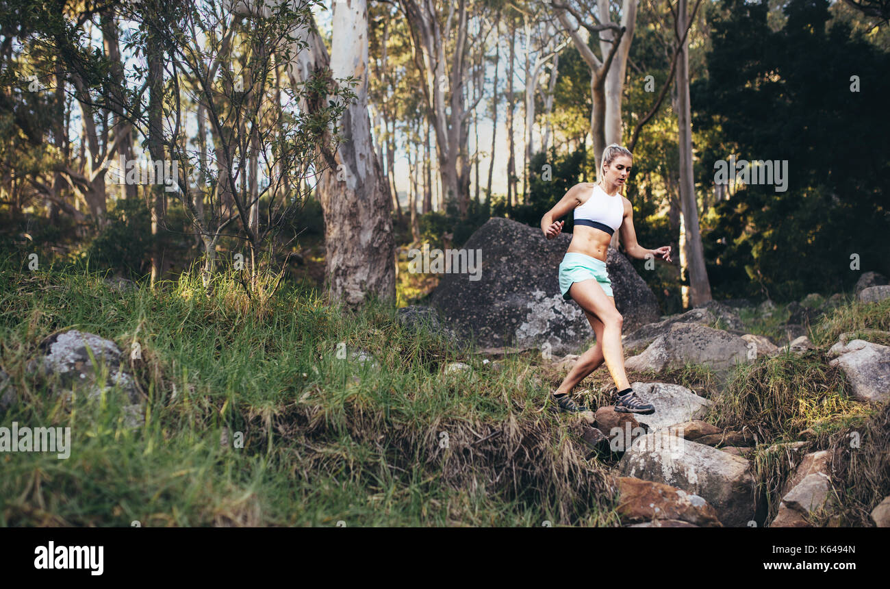Woman running through rocks and hard surface. Woman running on a rough ...