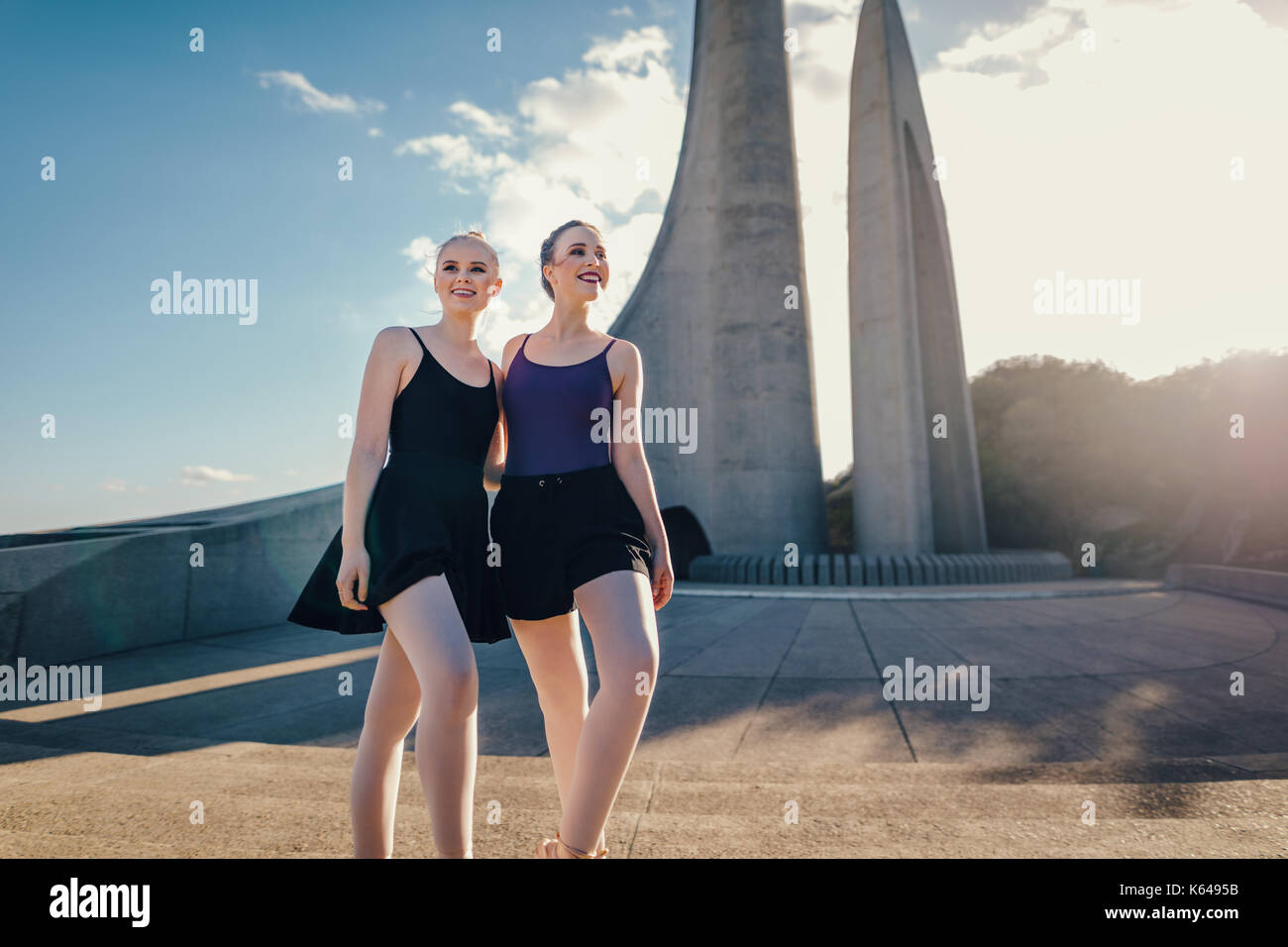 Two female ballet dancers standing together outdoors. Smiling ballet ...