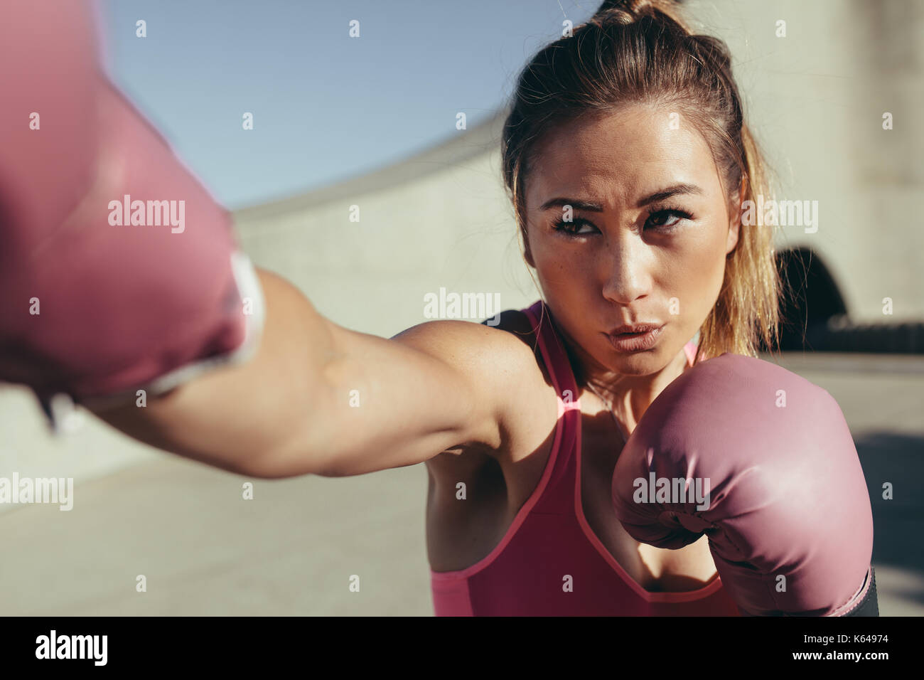 Fit young woman wearing boxing gloves doing punching workout. Female ...