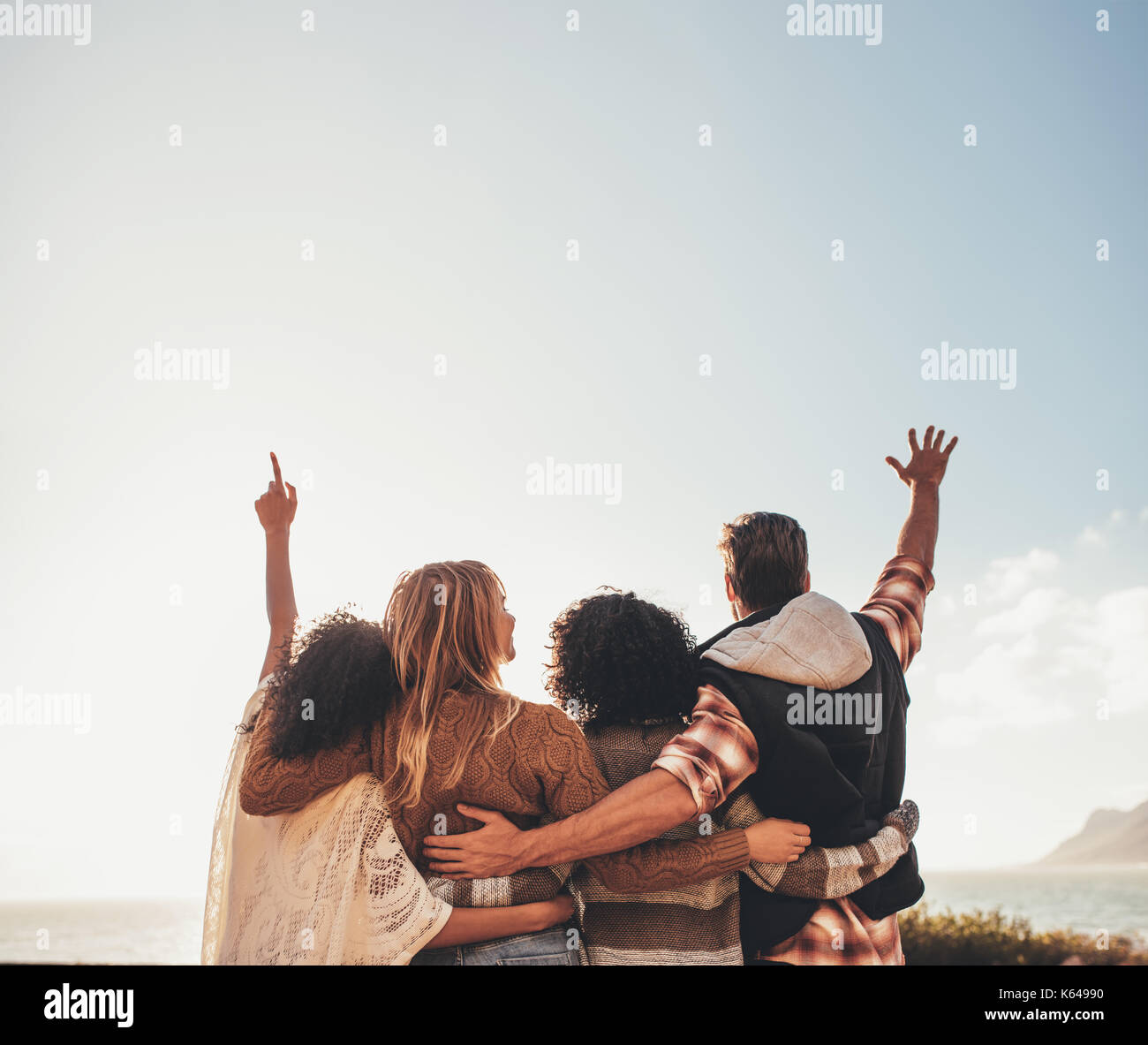 Four friends standing together with their arms raised. Group of man and ...