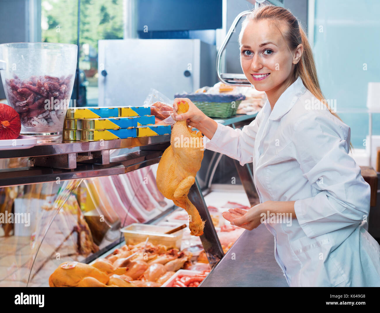 Smiling positive young woman seller in uniform holding fresh whole ...