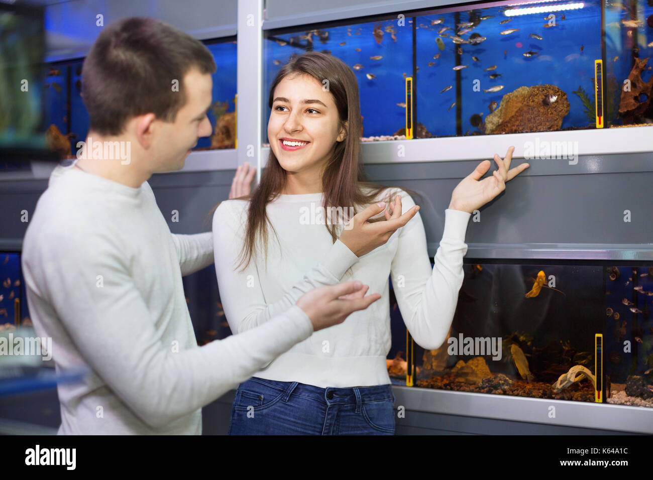 Positive smiling customers selecting tropical fish in aquarium tank ...