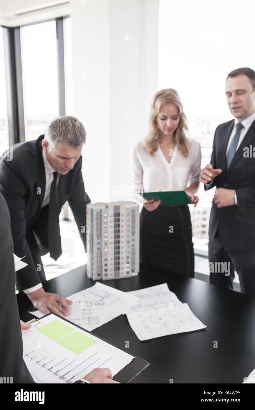Business meeting of architects and investors looking at model of modern ...