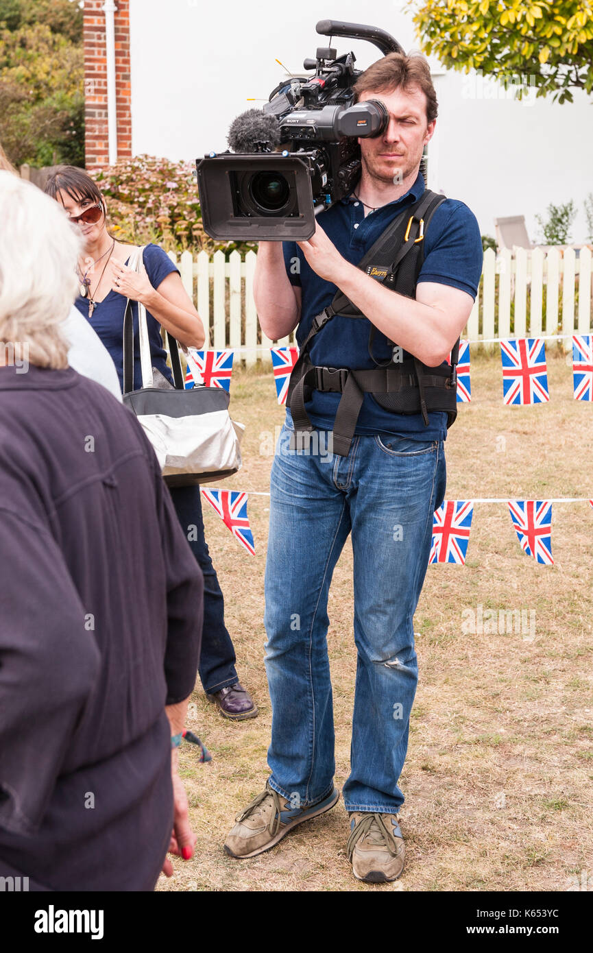 A TV cameraman at the village fete in Walberswick , Suffolk , England ...