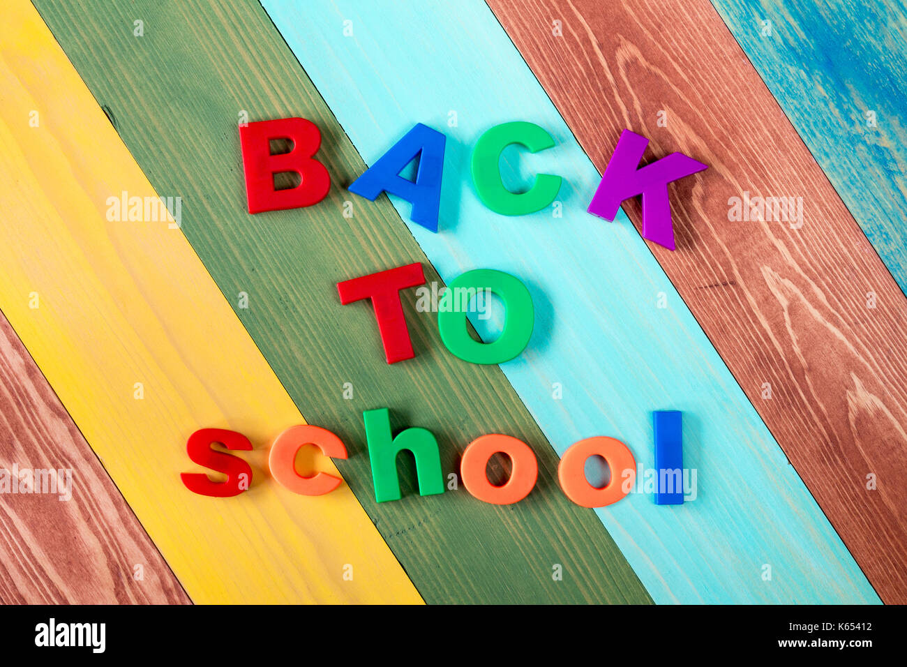 Sentence Back to school in colorful plastic letters over color wooden ...