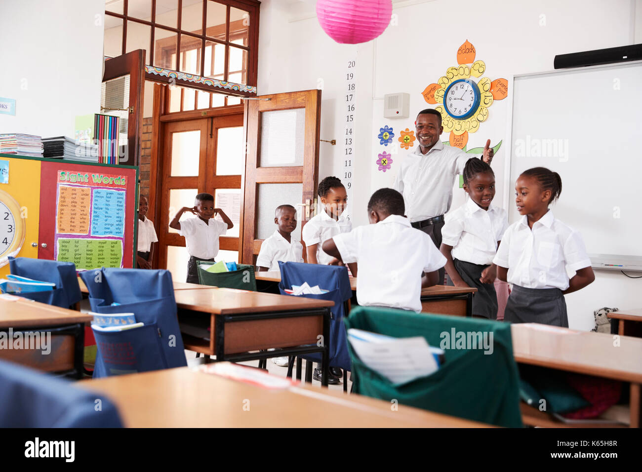 Teacher welcomes kids arriving to elementary school class Stock Photo ...