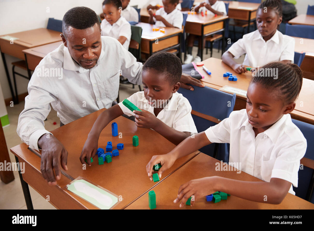 Teacher helping elementary school kids counting with blocks Stock Photo ...