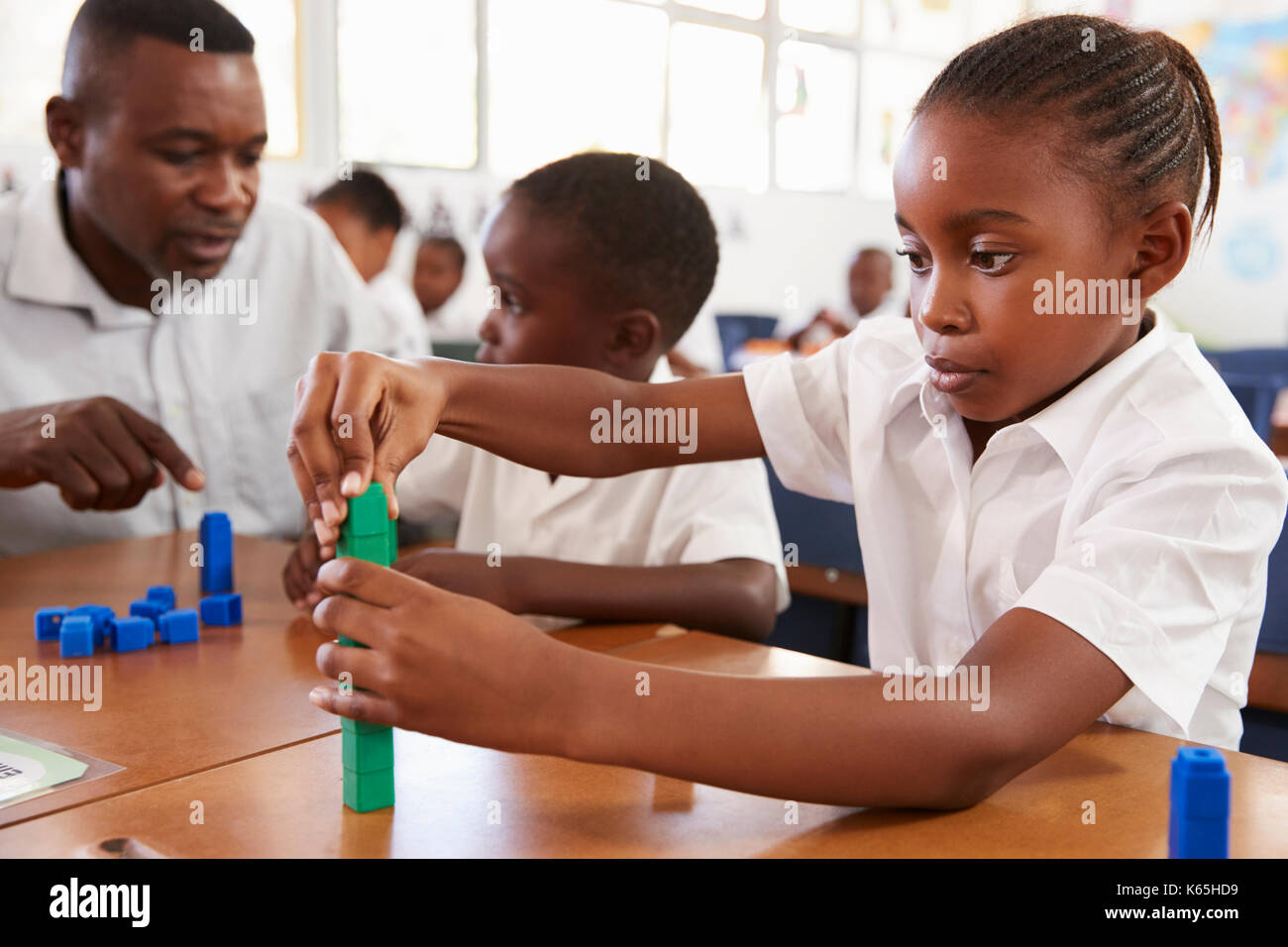 Teacher helping elementary school boy counting with blocks Stock Photo ...