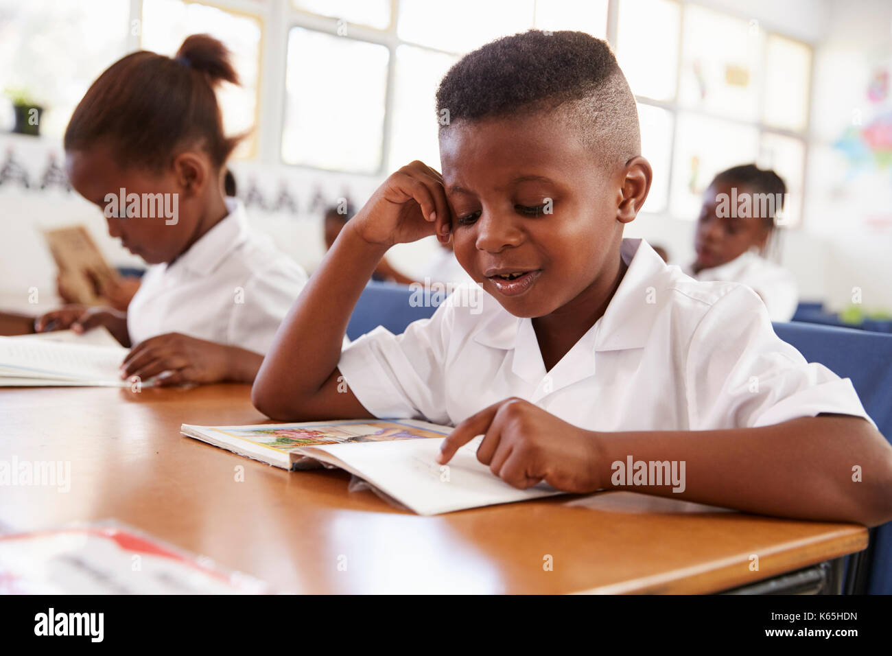 Elementary school boy reading a book at his desk in class Stock Photo ...