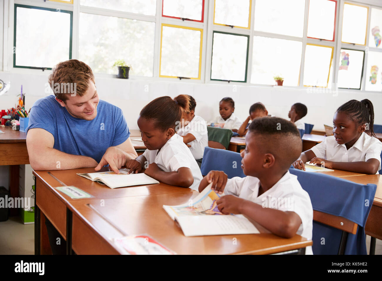 Volunteer teacher helping young girl at her desk in class Stock Photo ...