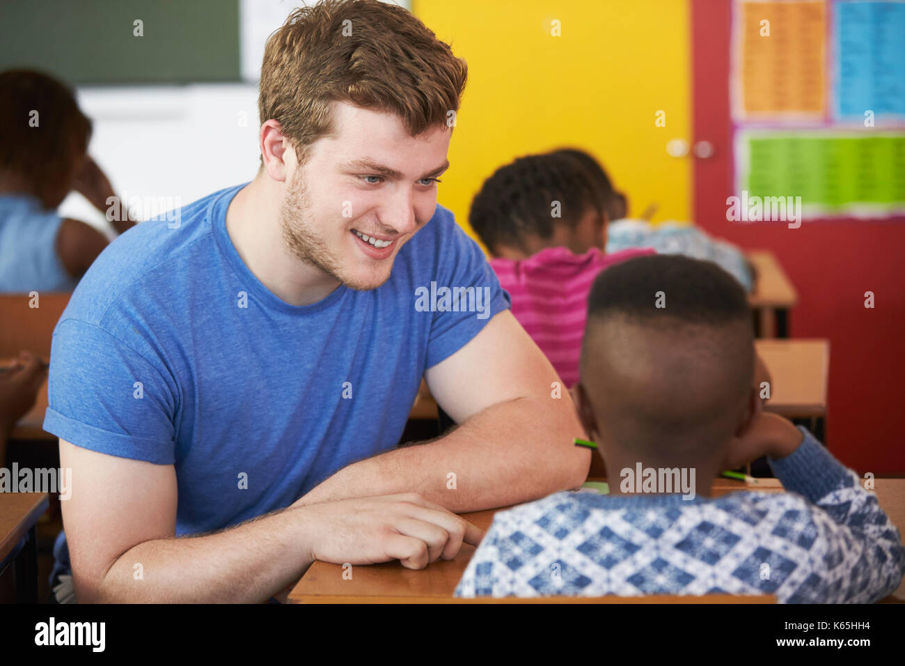 White male Volunteer teacher helping boy in elementary school class ...