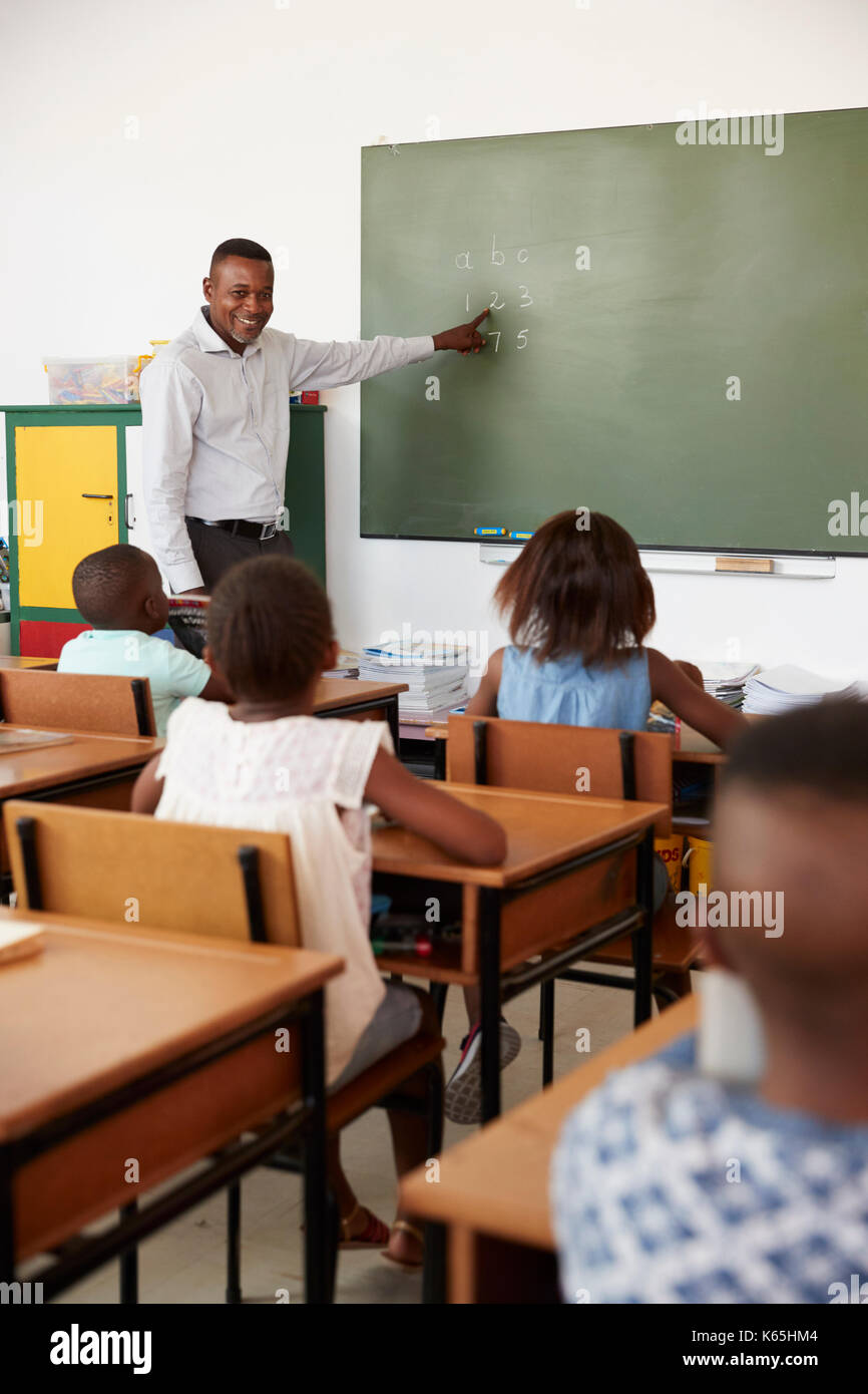 Teacher at chalkboard in elementary school class, vertical Stock Photo ...