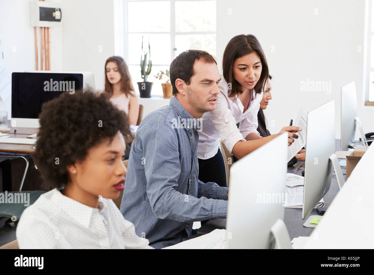 Colleagues talking at work in a busy open plan office, close up Stock ...