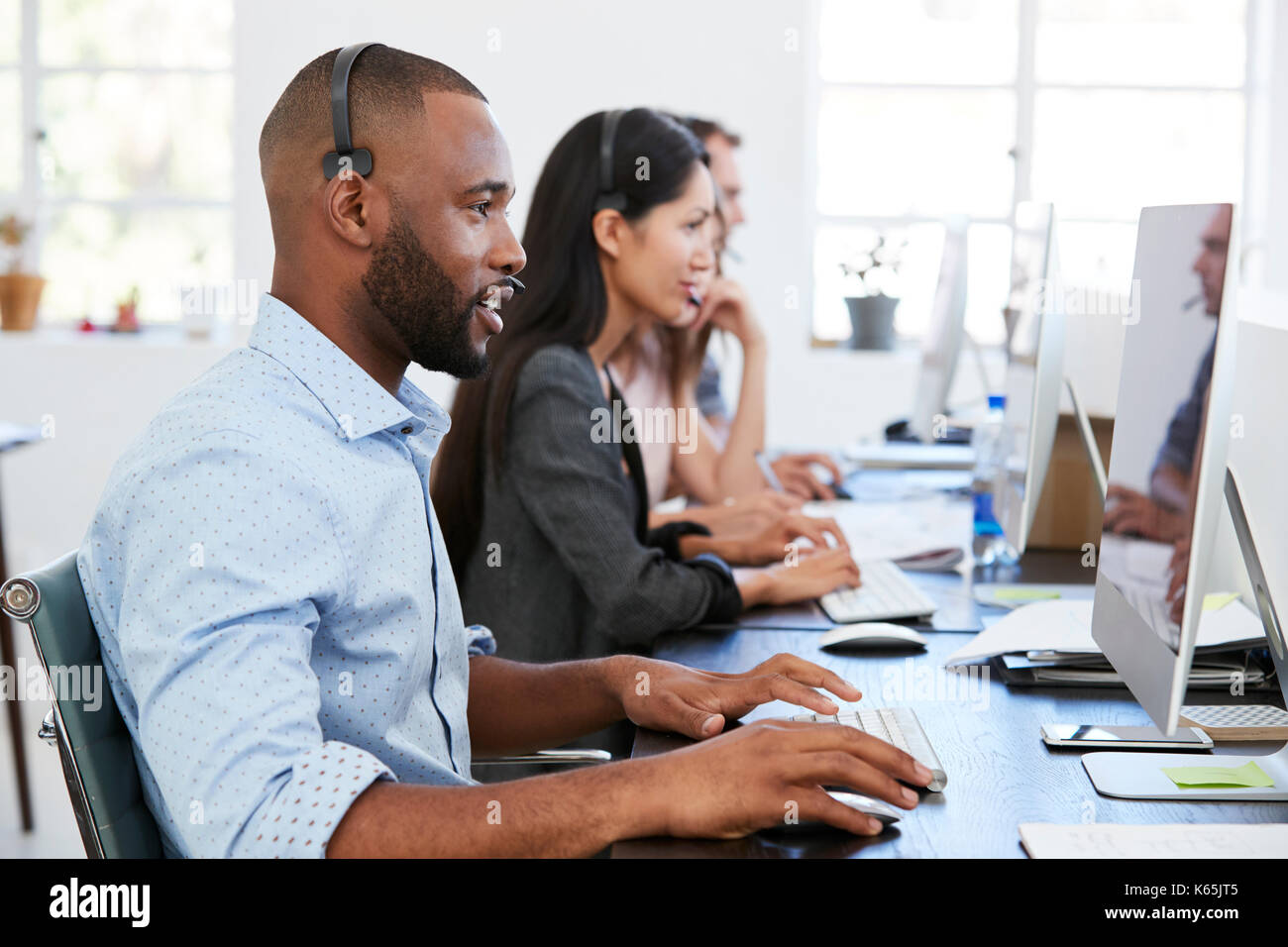 Young black man with headset working at computer in office Stock Photo ...
