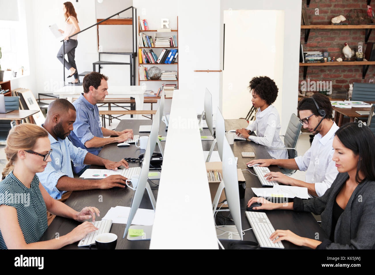Colleagues sit using computers in a busy open plan office Stock Photo ...