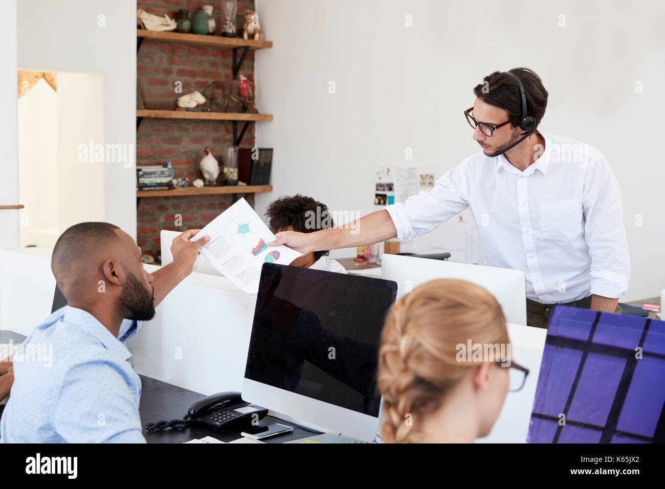 Man passing document in busy open plan office, close up Stock Photo - Alamy