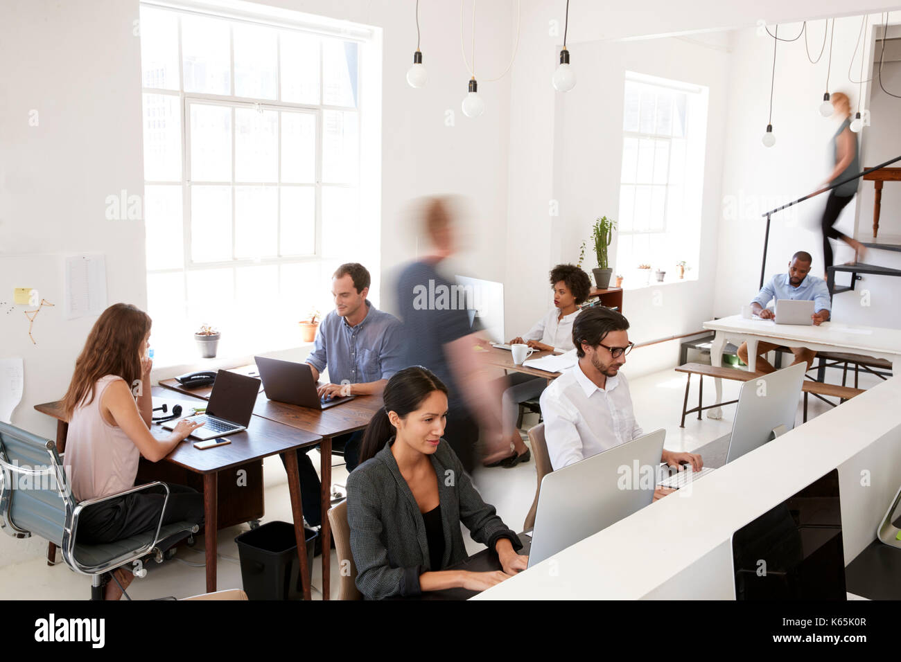 Young business colleagues working in a busy open plan office Stock ...